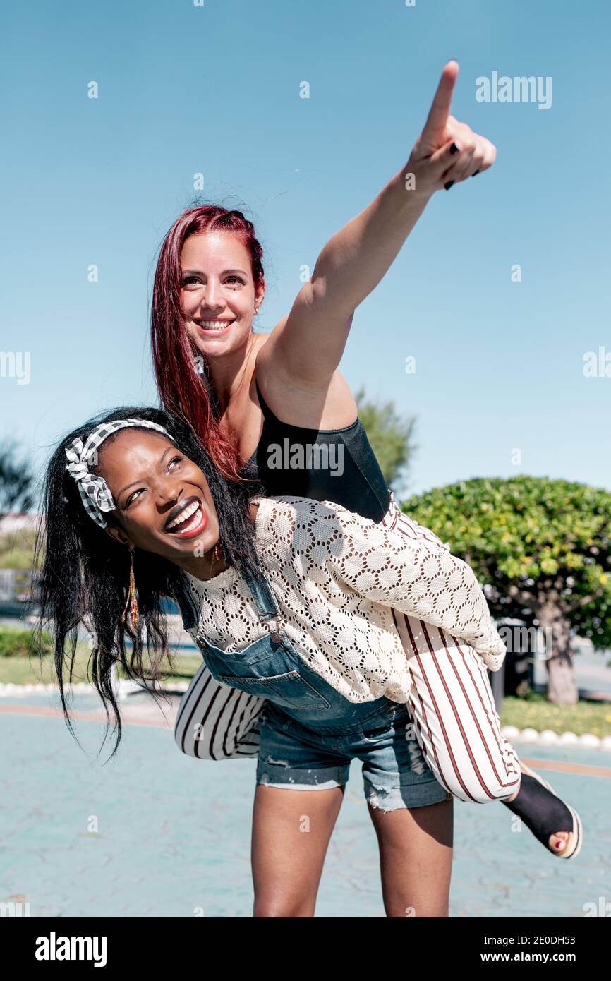 Laughing African American Woman giving piggyback ride to girlfriend ...