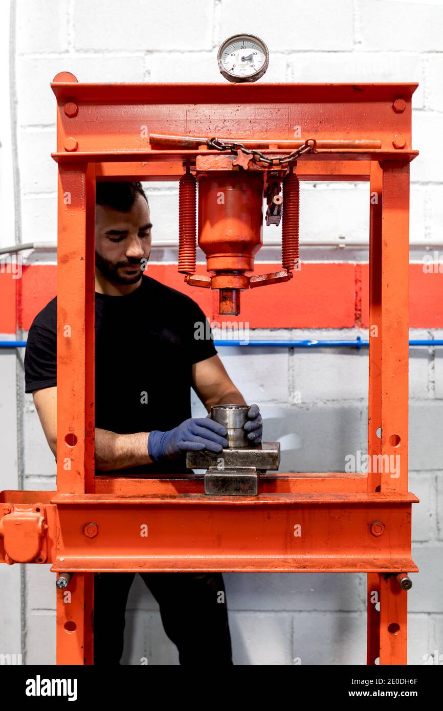 Side view low angle of male technician using hydraulic press for car ...
