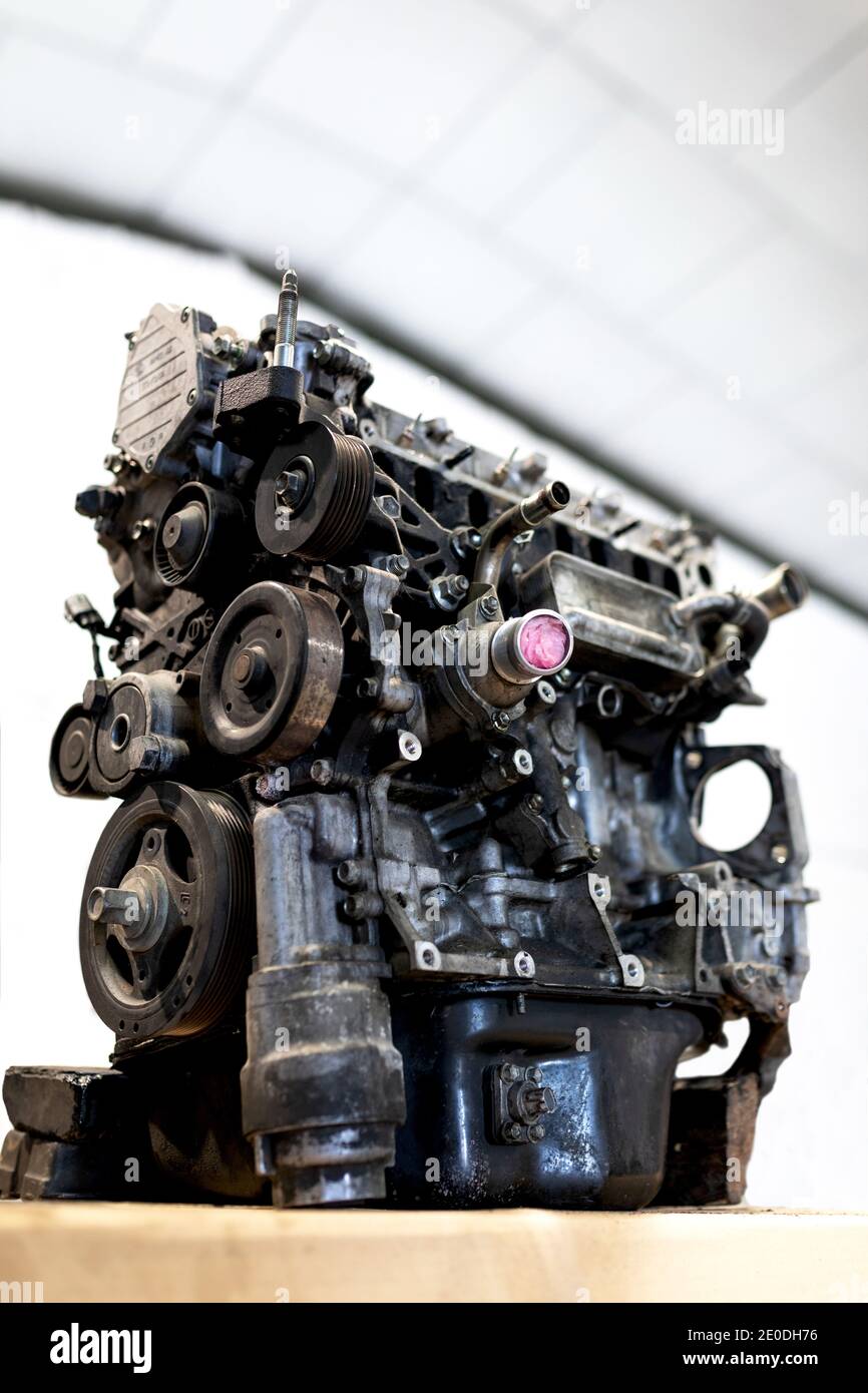 Low angle of dirty car engine placed on table in bright facility of car ...