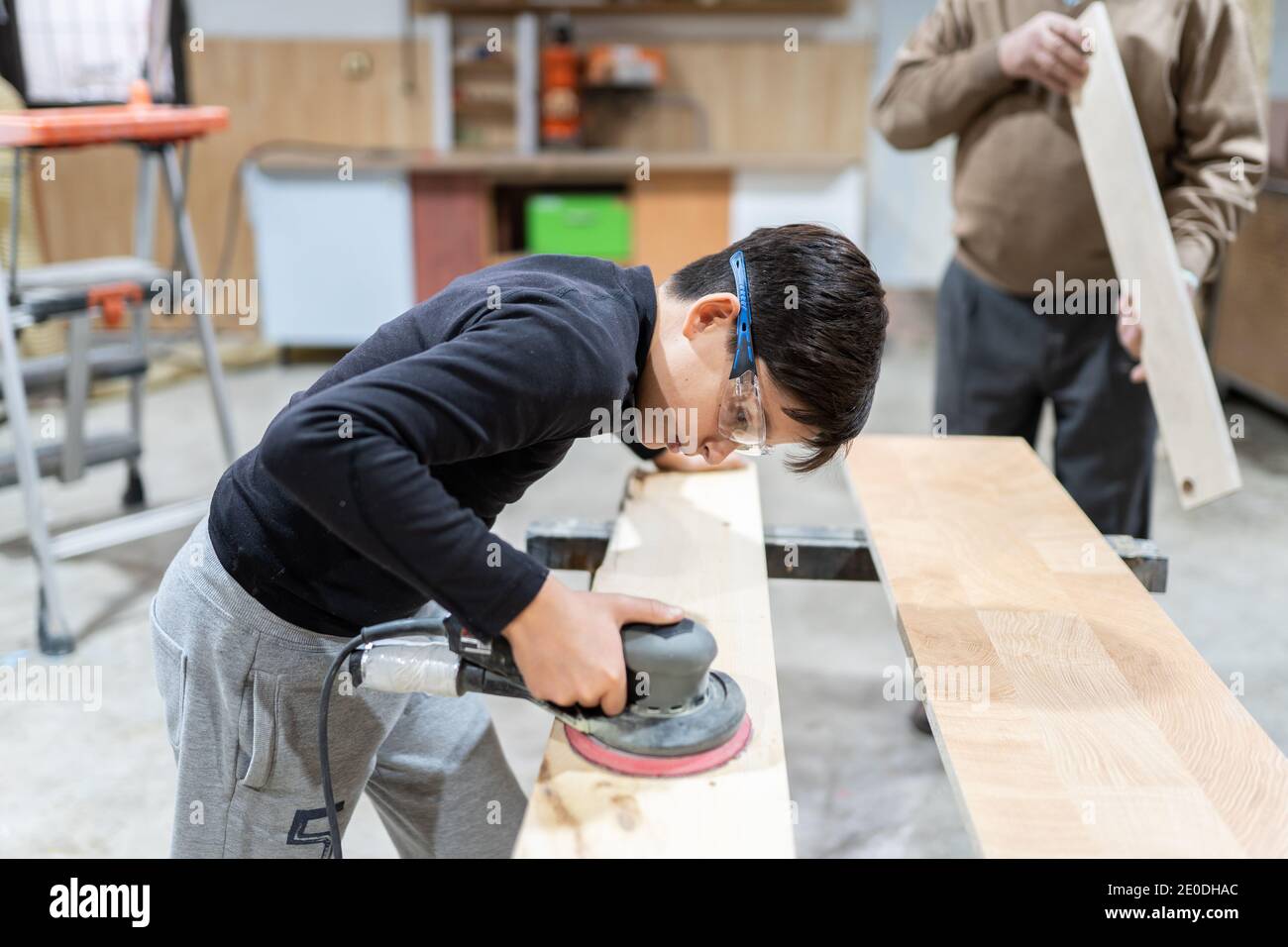 Side view of concentrated boy in casual clothes and goggles smoothing ...