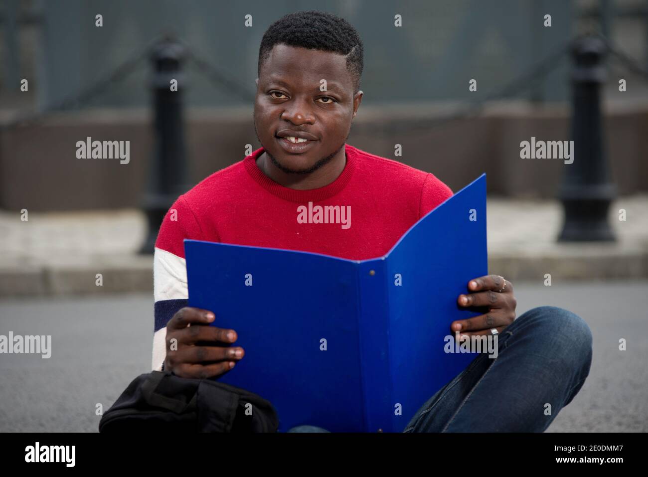 Handsome college man reading notes in notebook on campus.Happy student ...