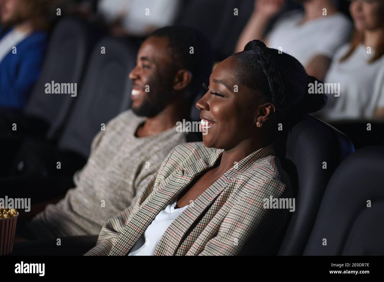 Side view of young african couple enjoying film in movie theater ...