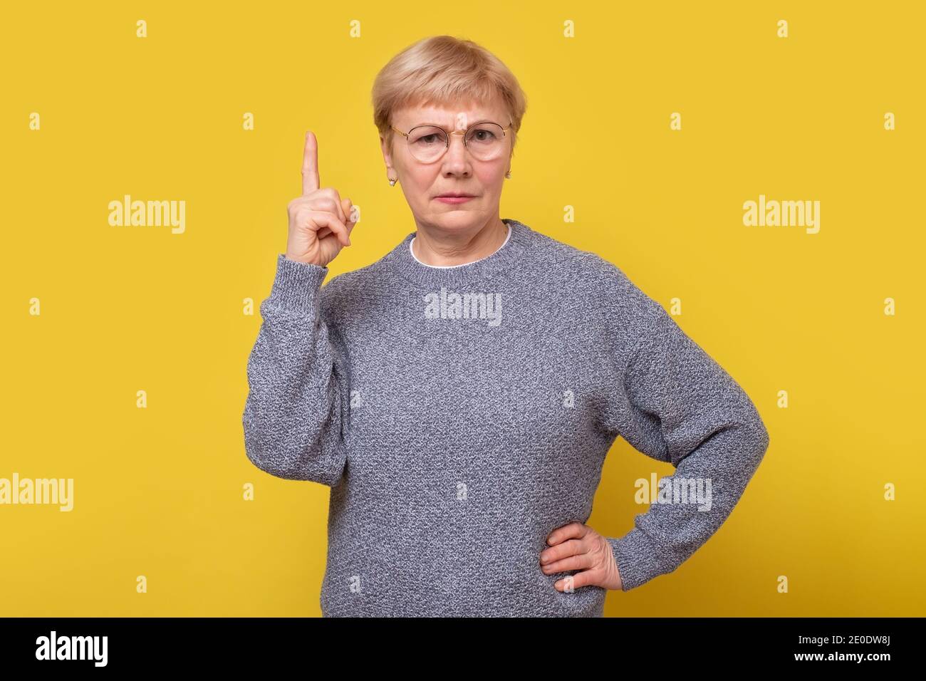 Senior woman pointing up looking angry, indicating direction with ...