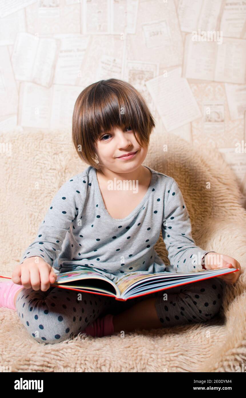 A little smiling girl with blue eyes is reading a book Stock Photo - Alamy