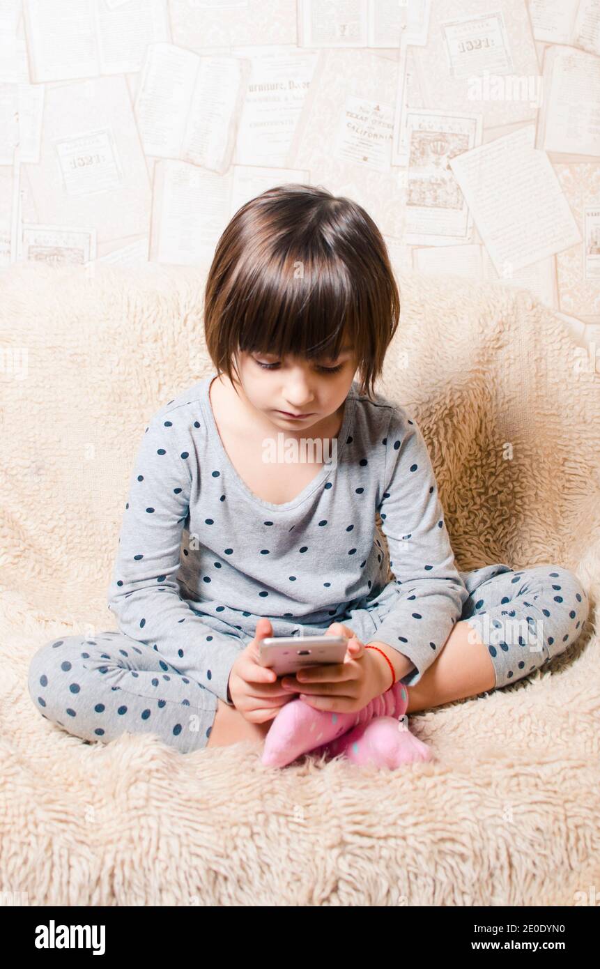 Little girl is looking at the mobile phone Stock Photo - Alamy