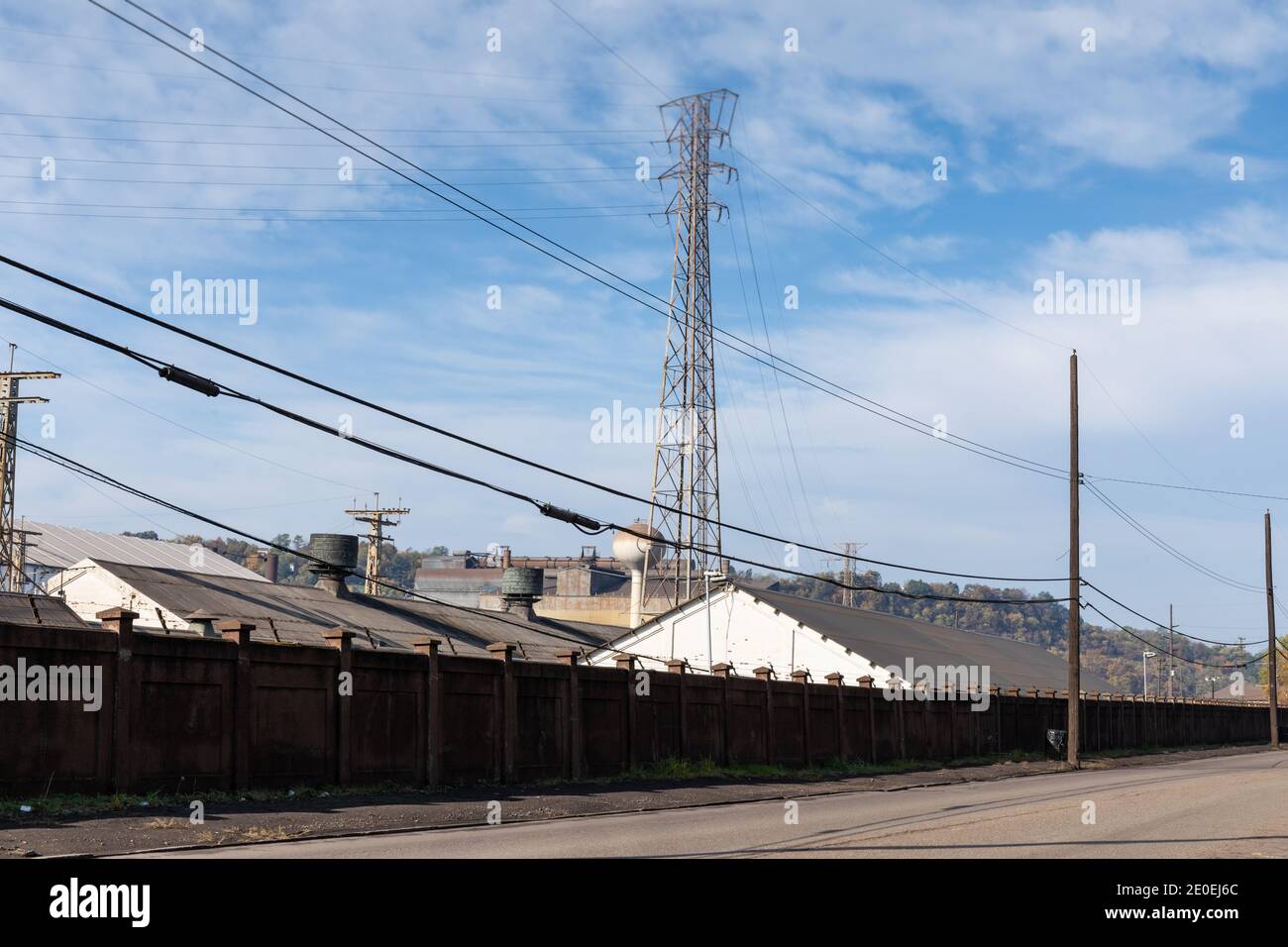 Large steel mill manufacturing facility behind a large wall, street ...