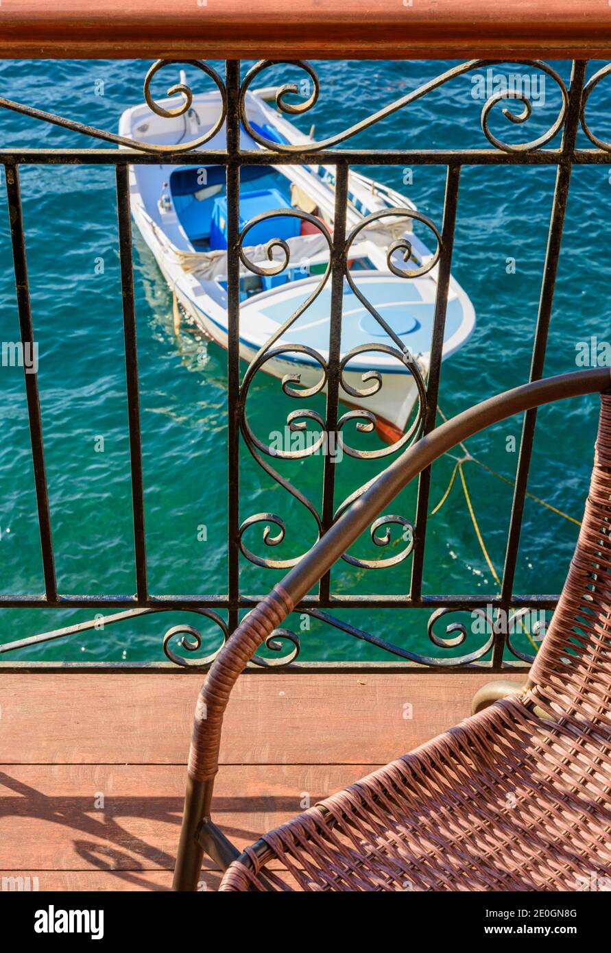 View through a wrought iron balcony over a small boat on the sea, Symi ...