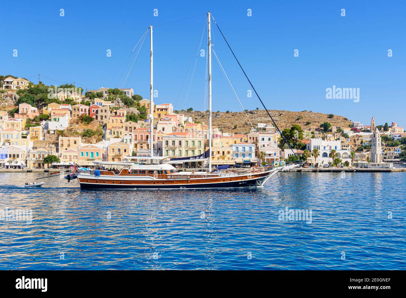 A Turkish gulet departs Gialos Harbour, Symi Island, Dodecanese, Greece ...