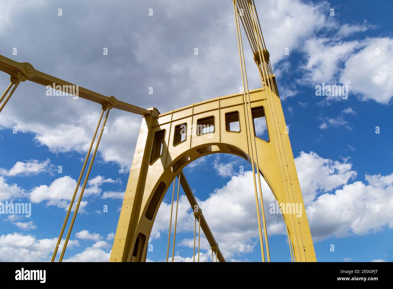 Riveted metal self anchored suspension bridge painted yellow against a ...