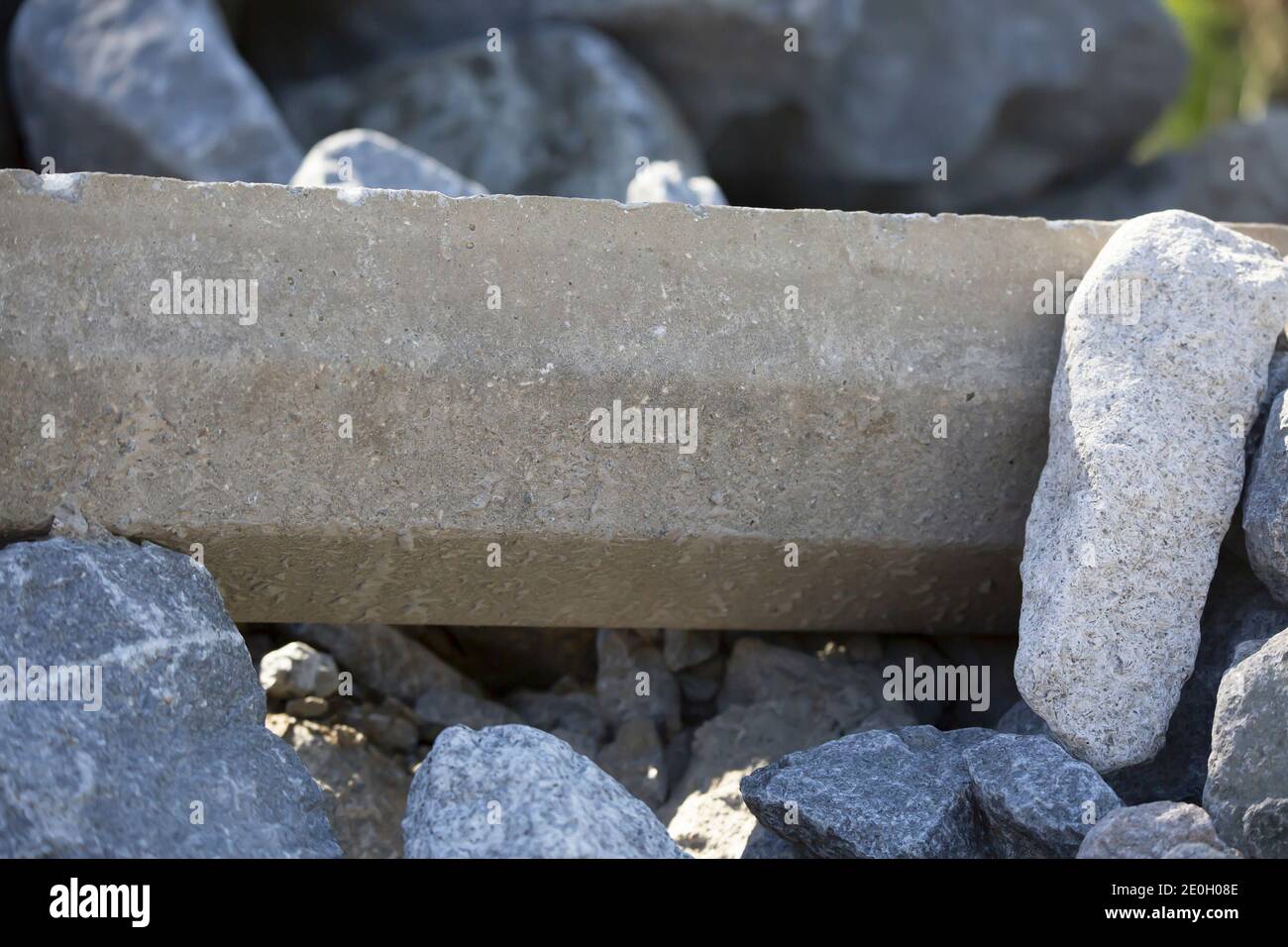 Cement bumper torn from the ground and stacked on a pile of granite ...