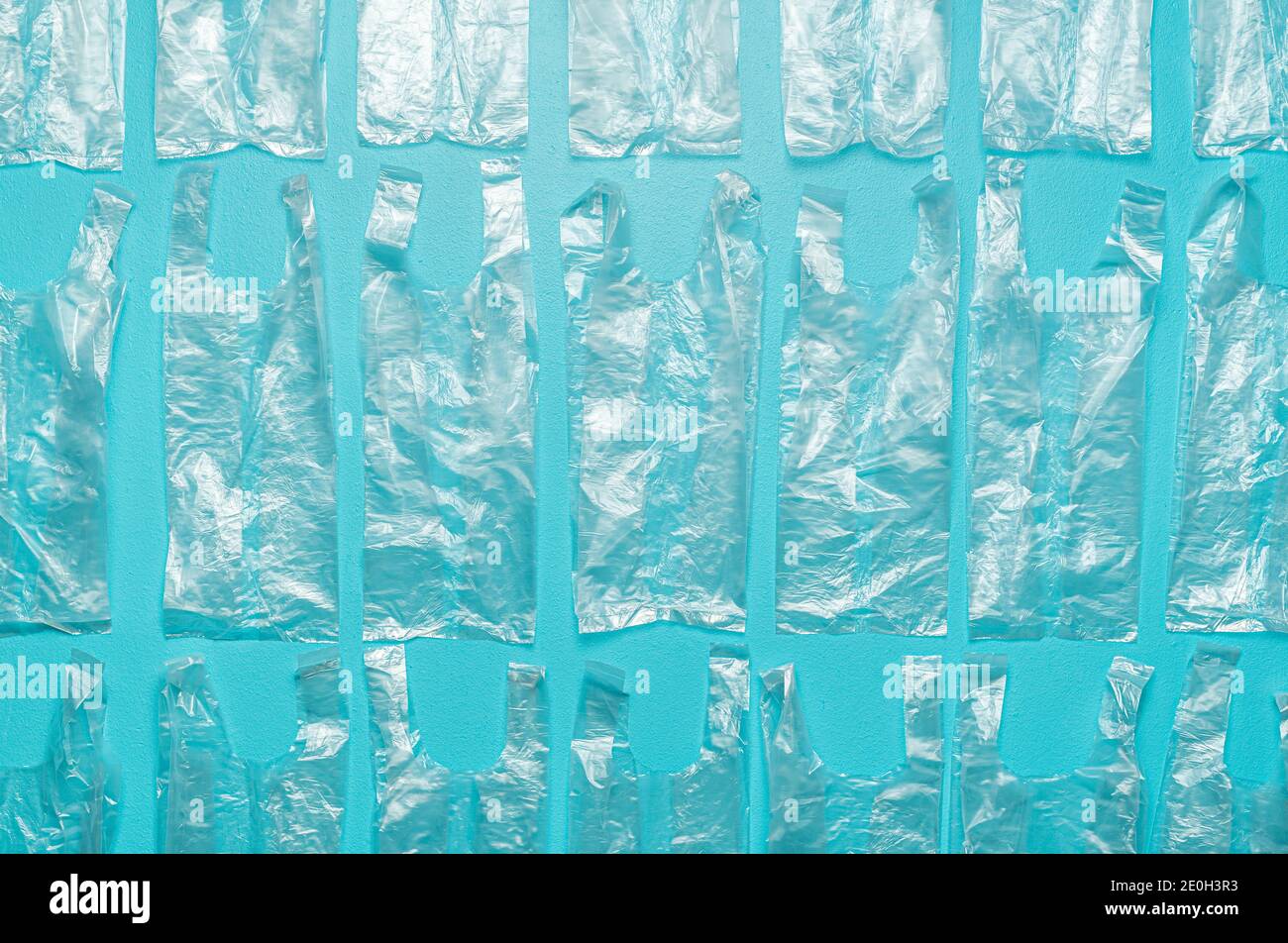 Flat lay with a multitude of plastic bags aligned on a blue background ...