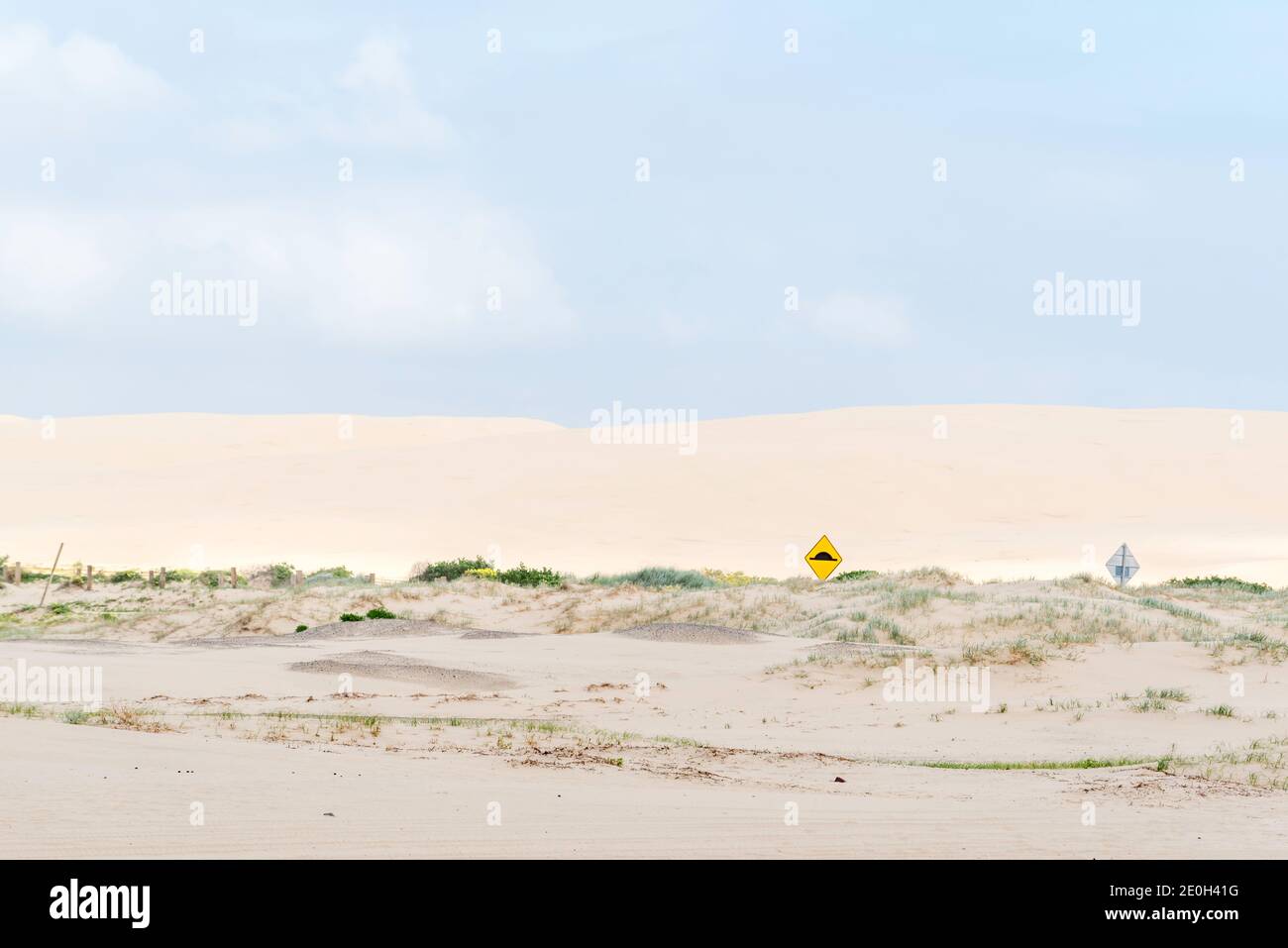 Road signs are almost buried under shifting sand dunes at Birubi Beach ...