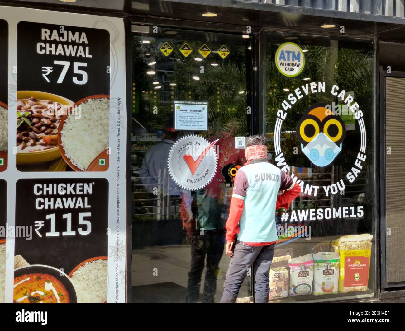 Hyperlocal delivery guy in blue Dunzo uniform standing outside 24Seven ...