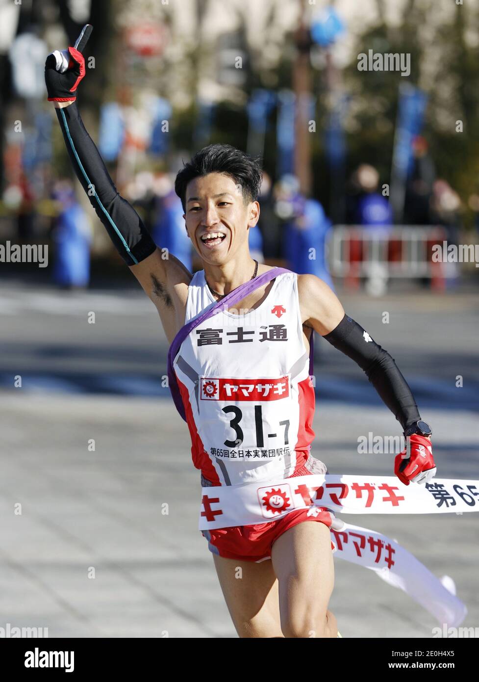 Fujitsu anchor Yuhei Urano crosses the finish line of the national corporate ekiden road relay ...