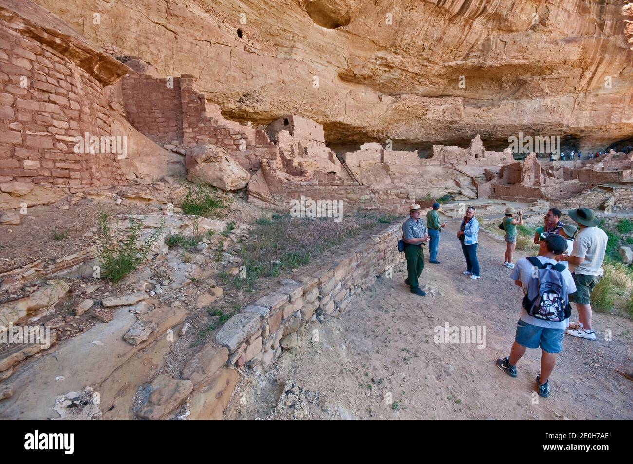 Park guide and visitors at Long House cliff dwelling in alcove at ...