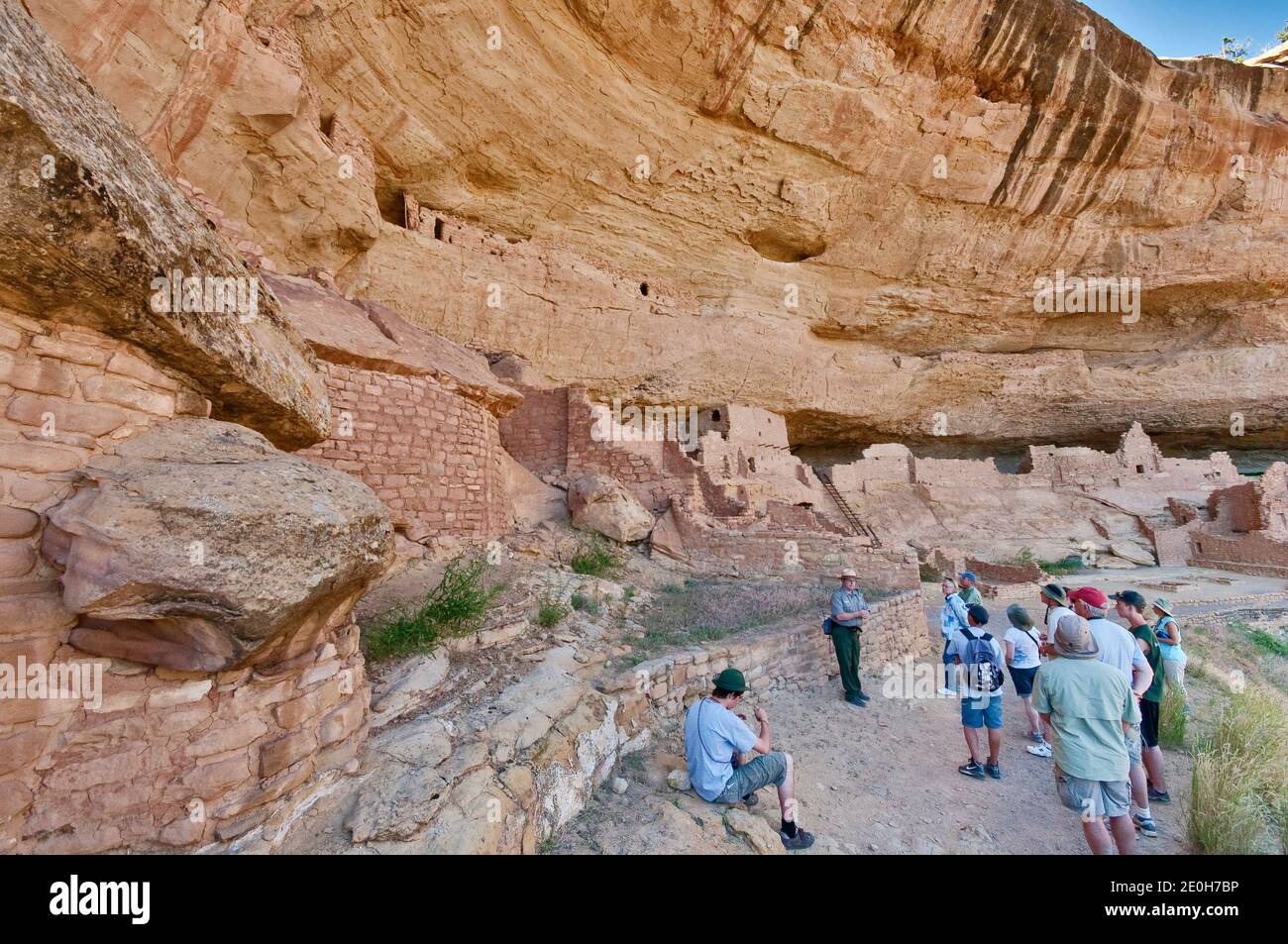 Park guide and visitors at Long House cliff dwelling in alcove at ...