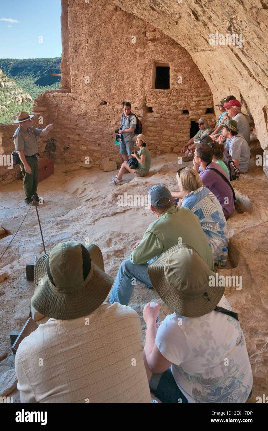 Park guide and visitors at Long House cliff dwelling in alcove at ...