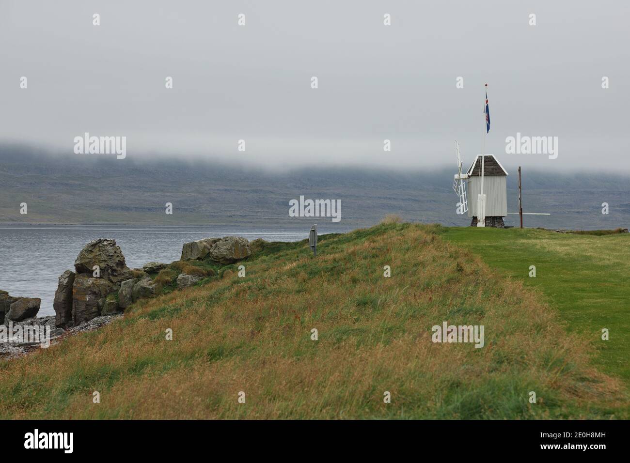Windmill and Icelandic flag in Vigur island in a cloudy and windy day ...