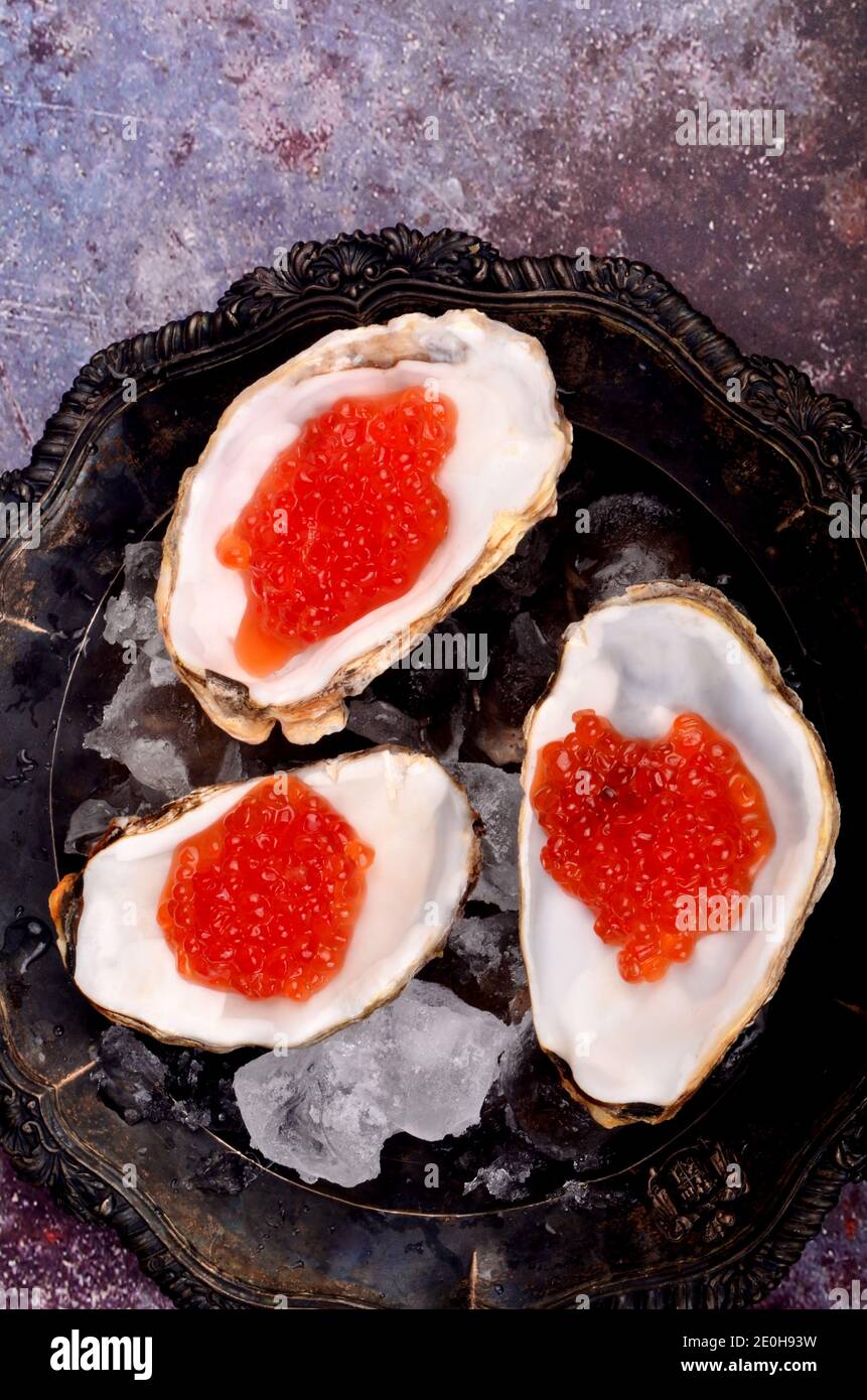 Fresh red salmon caviar in the three oyster shells on ice in vintage ...