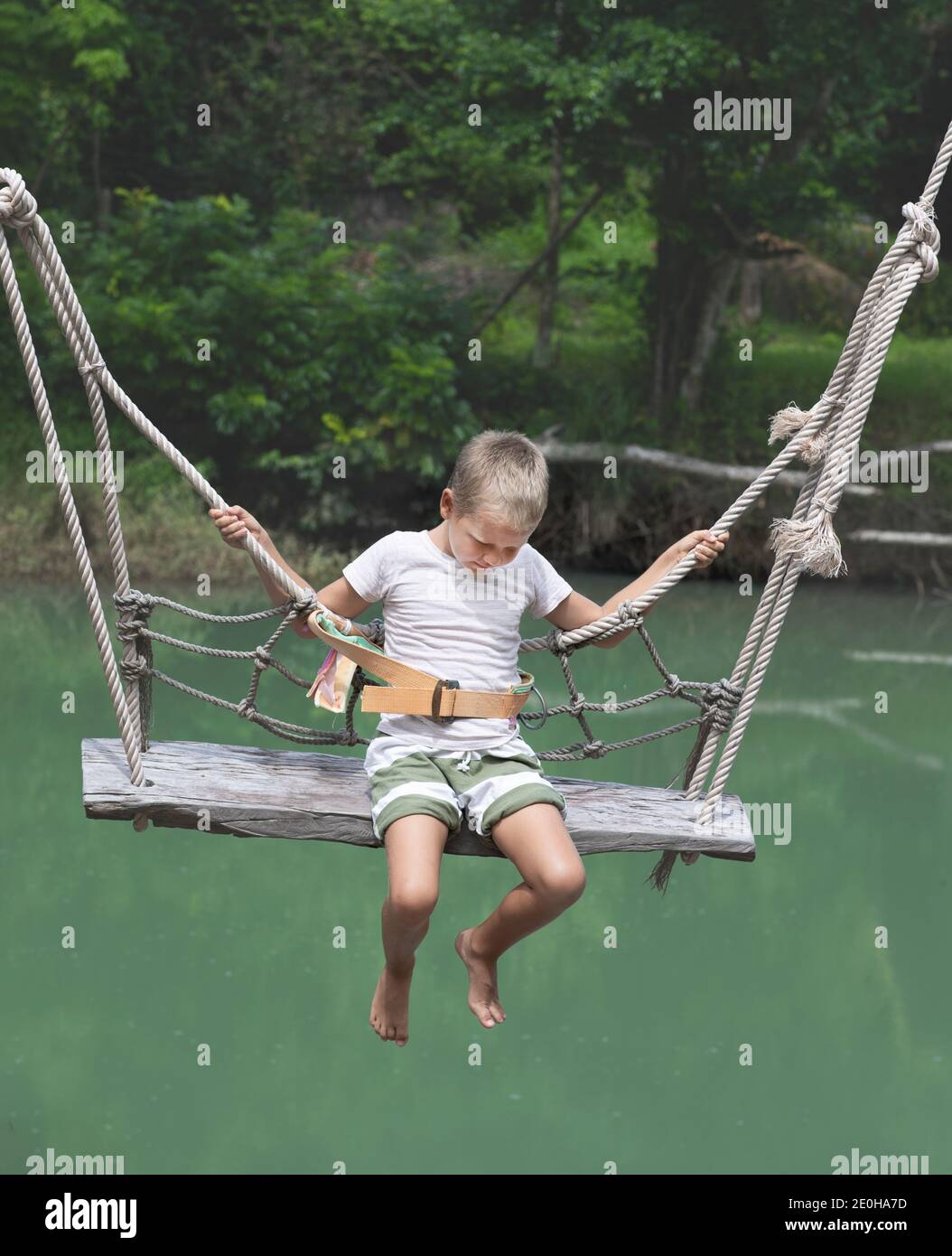 Little boy swinging on a swing over the river Stock Photo - Alamy