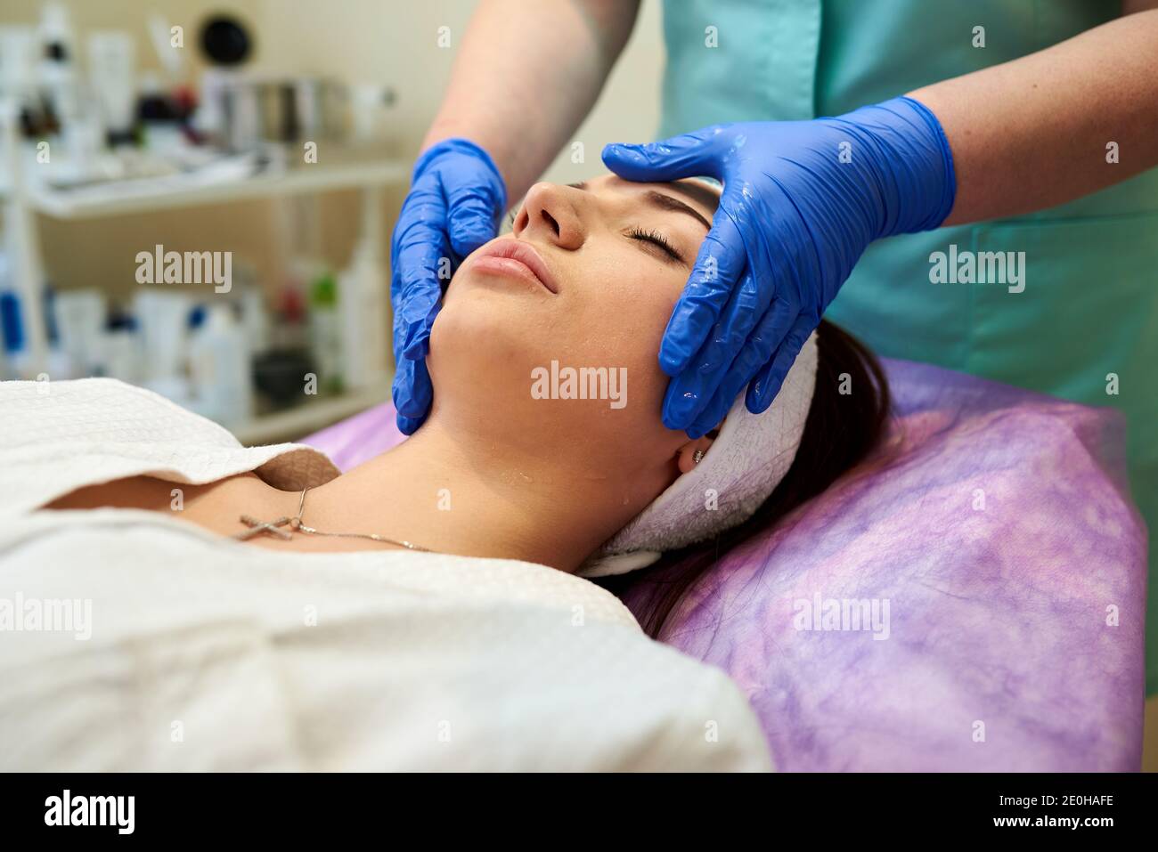 Cosmetologist masseuse cleaning woman face at spa in cosmetic cabinet ...