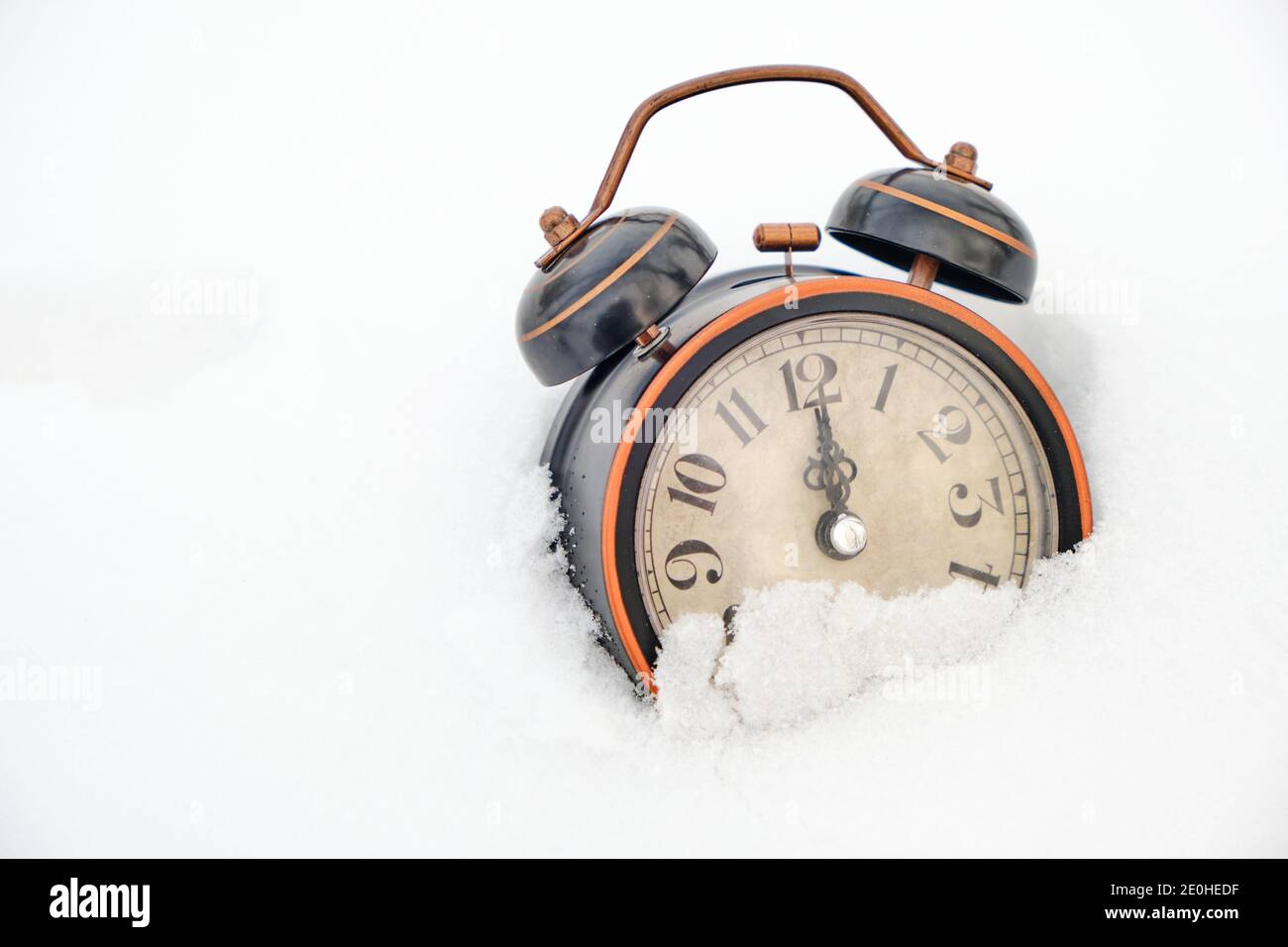 Old retro alarm clock in winter in snow on white background shows ...