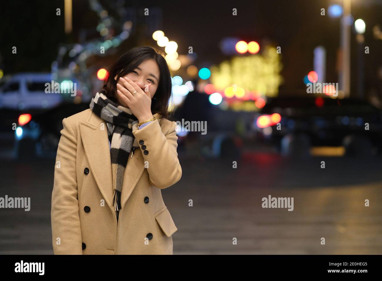 mid shot of one beautiful Asian young woman laughing behind hand at ...