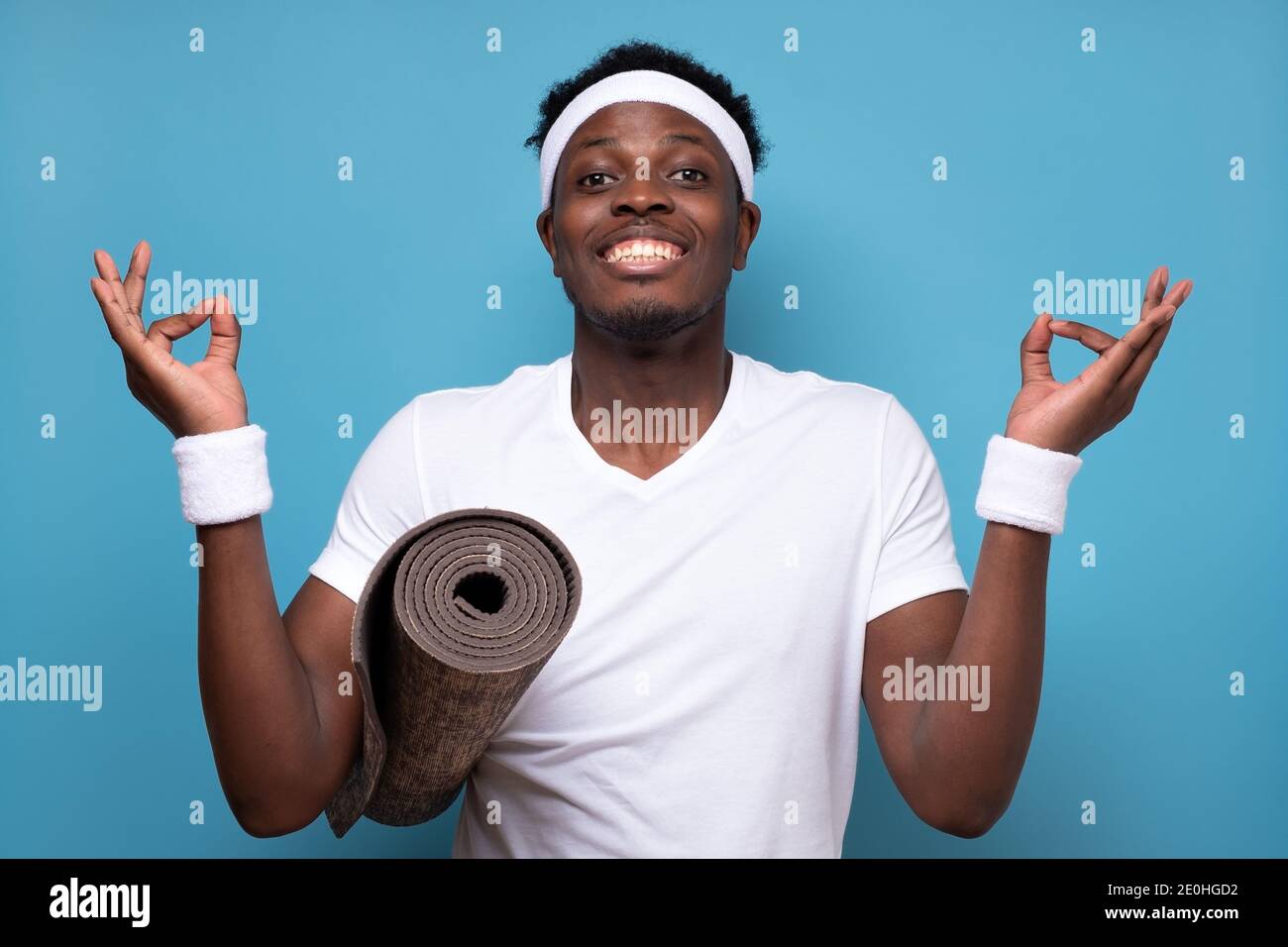 Young african yoga teacher meditating holding yoga mat. Studio shot on ...