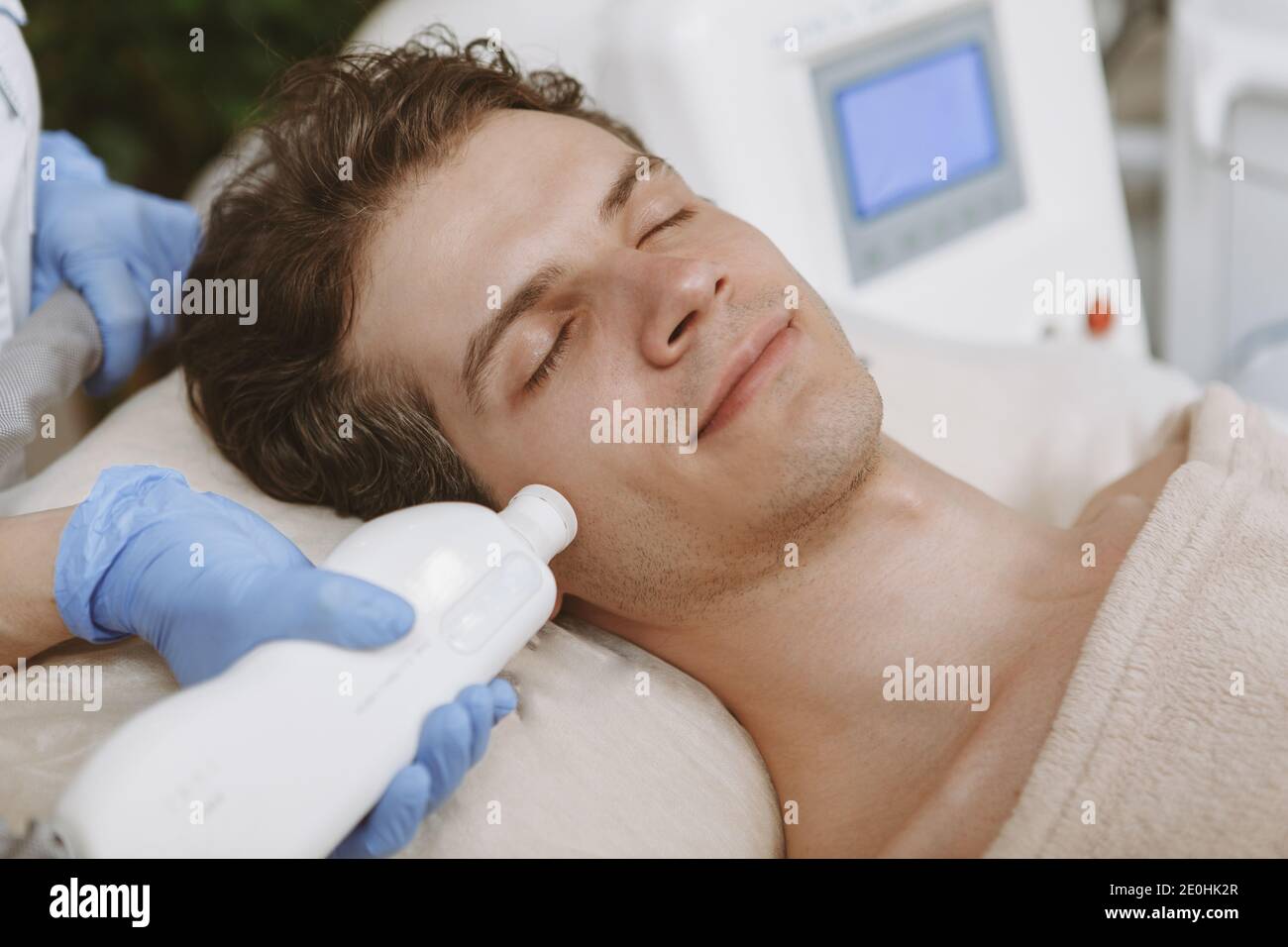 Close up of a male client relaxing during facial laser treatment ...