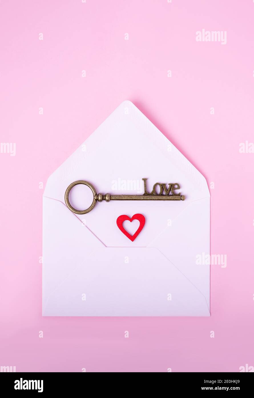 Love key and red heart in an envelope on a pink background, top view ...