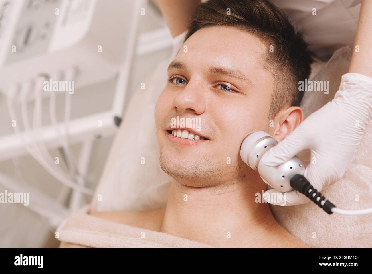 Happy handsome man having skincare treatment by professional ...