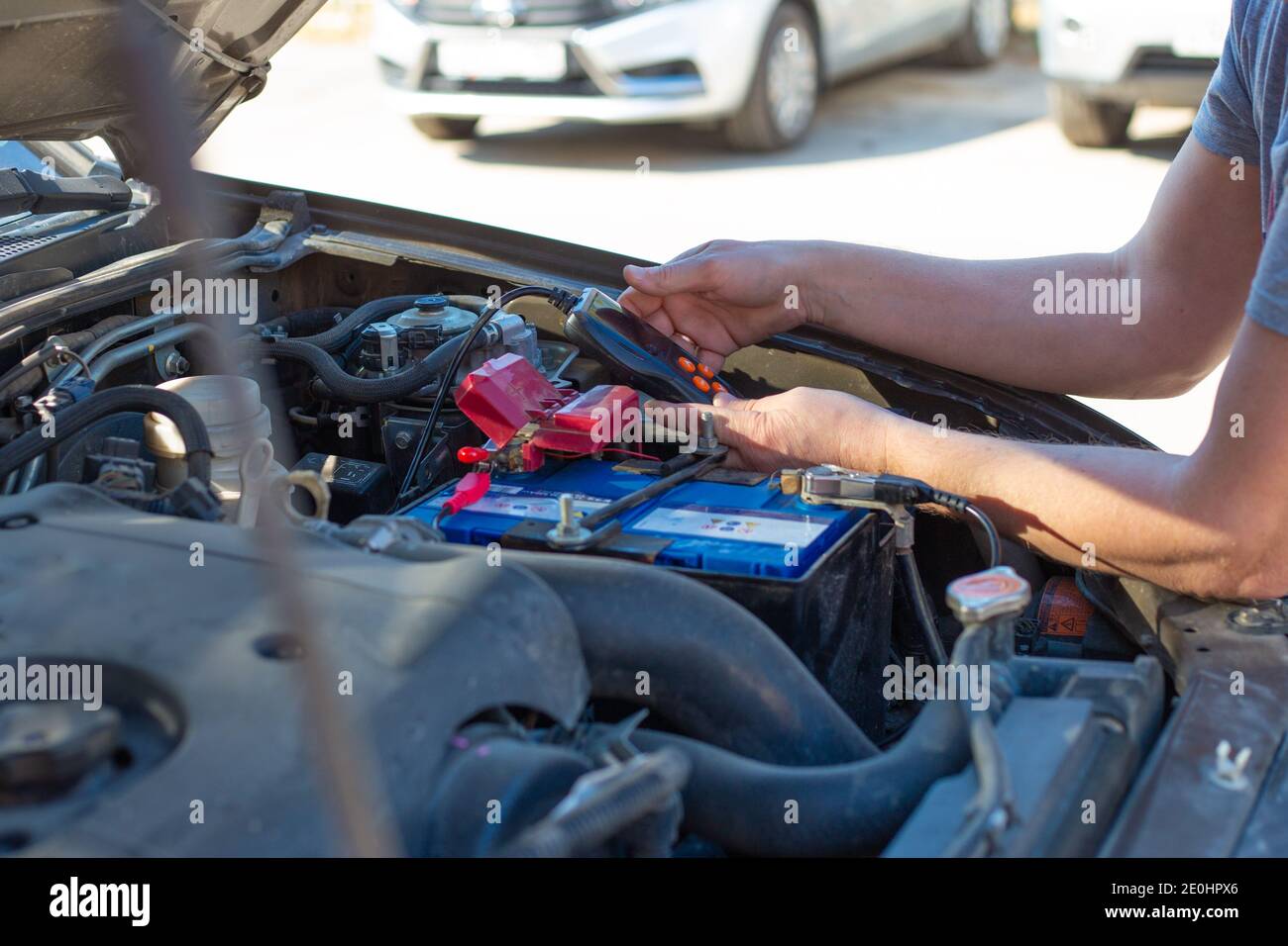 Checking the battery charge with a tester. The mechanic raised the hood ...