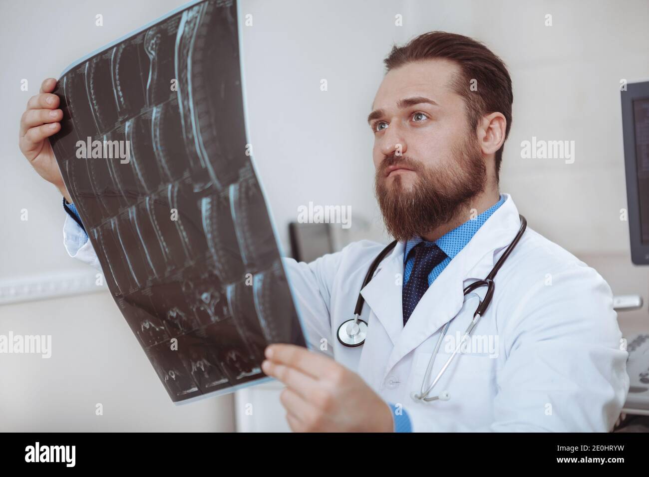 Close up of a handsome bearded male doctor examining x-ray scans of a ...
