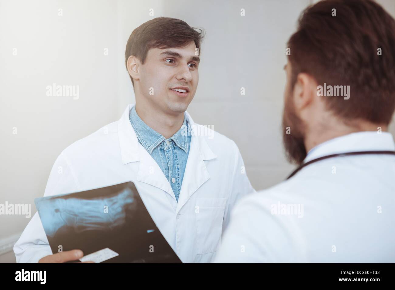 Handsome male doctor talking to his colleague, holding x-ray scan of a ...