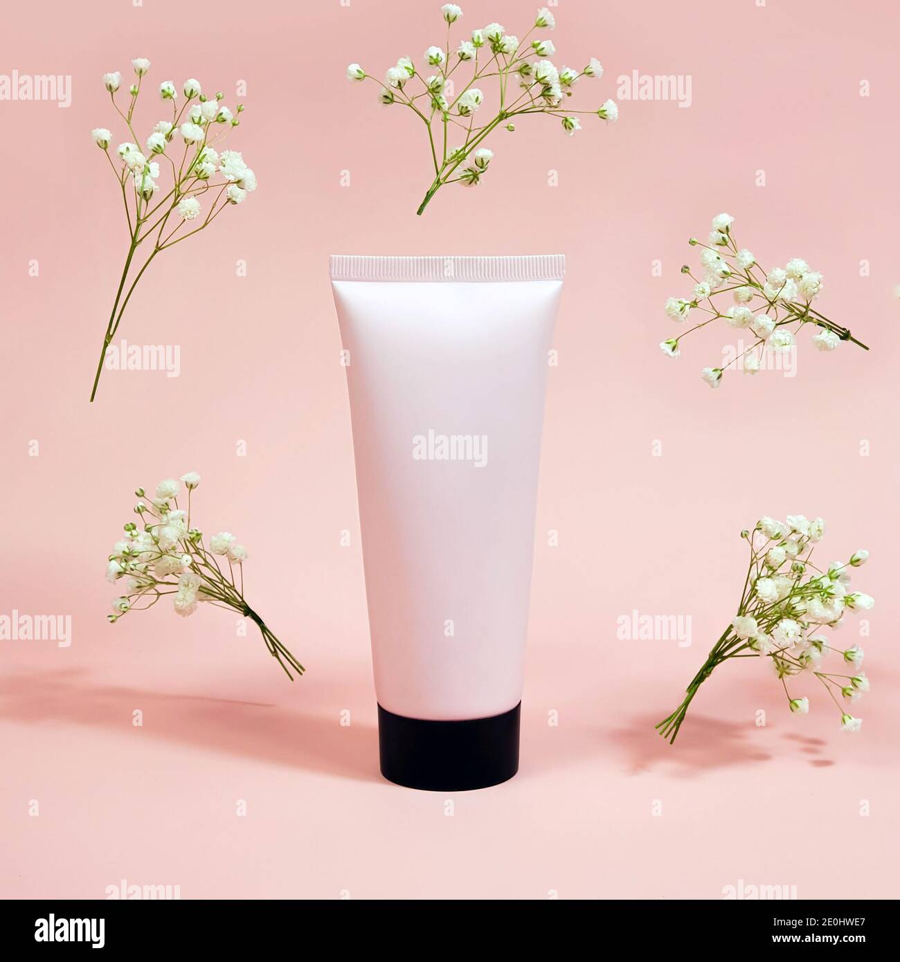 Pink squeeze bottle cosmetic tube with black cap and flying gypsophila ...