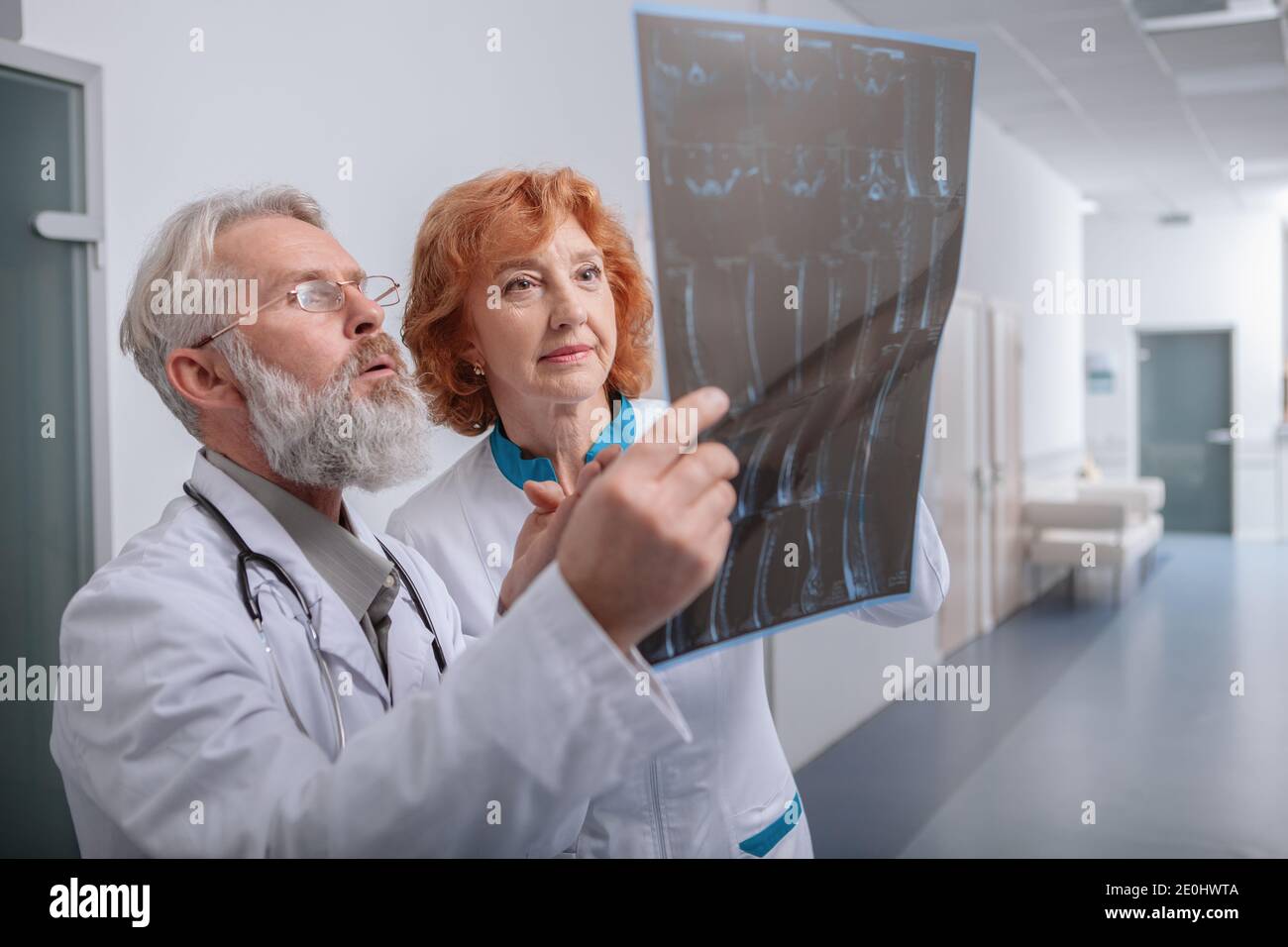 Elderly male and female doctors examining MRI scan together. Medical ...