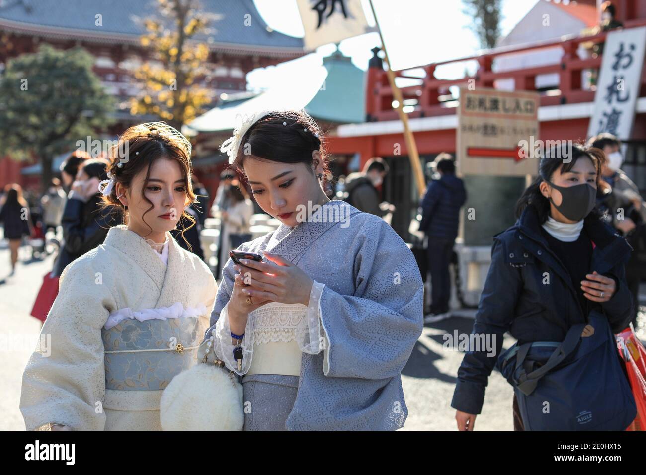 Girls wearing face masks and kimono take photos in front of the Sensoji ...