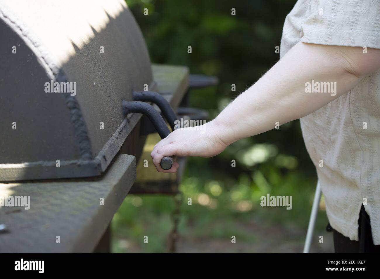 Woman opening a barbecue grill in a park Stock Photo - Alamy