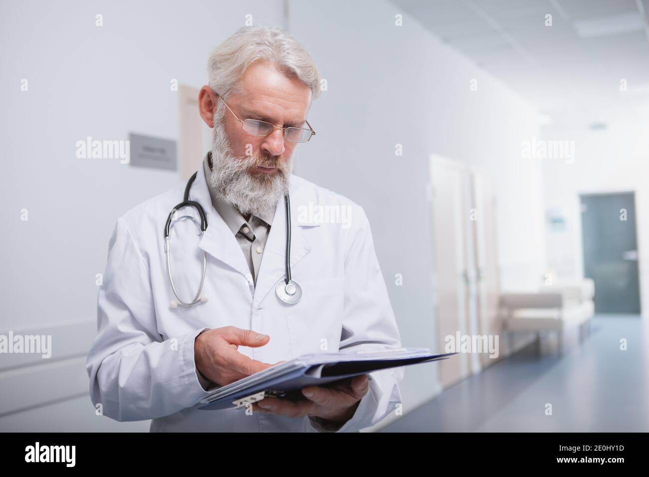 Professional medical worker reading documents on his clipboard, working ...