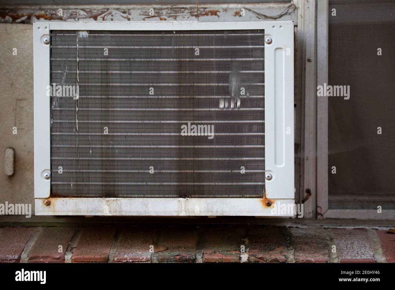 Air conditioner in the window of a red brick building, bolstered by ...