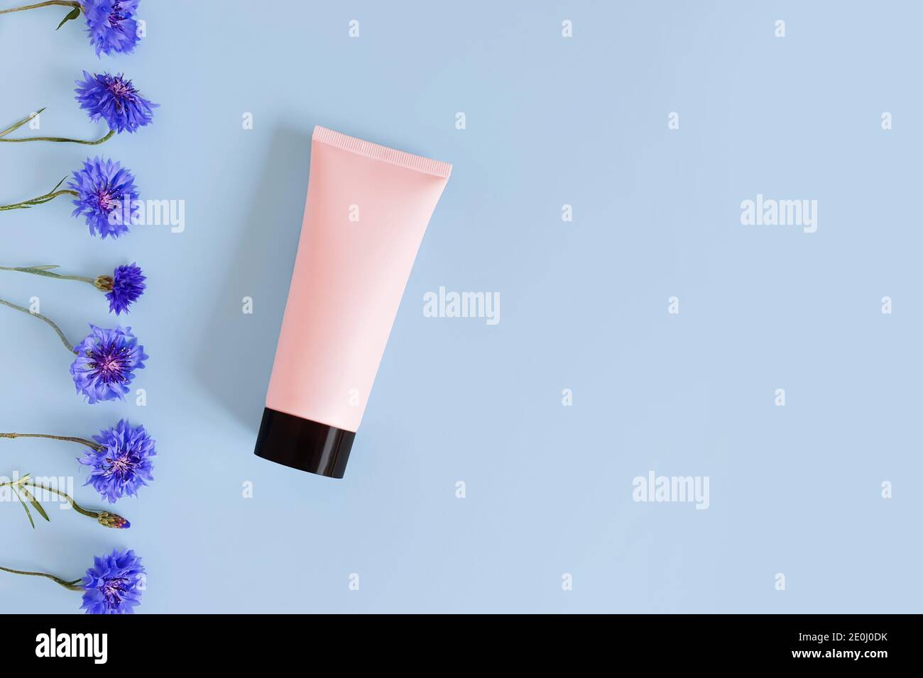 Mockup of pink squeeze cosmetic tube with black cap and blue flowers on ...
