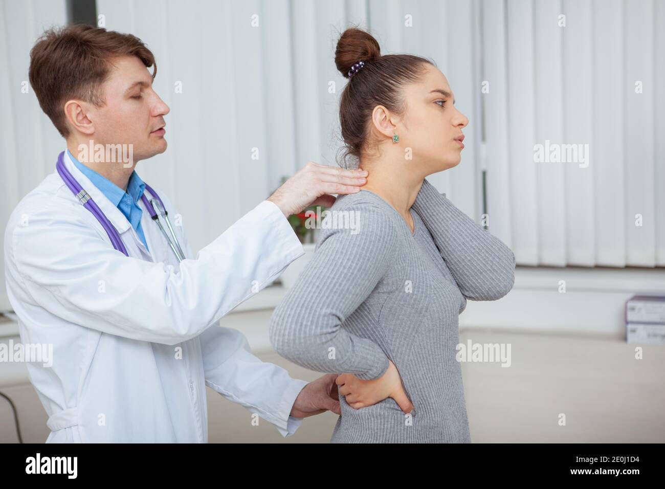 Young woman suffering from back pain visiting doctor at the hospital ...