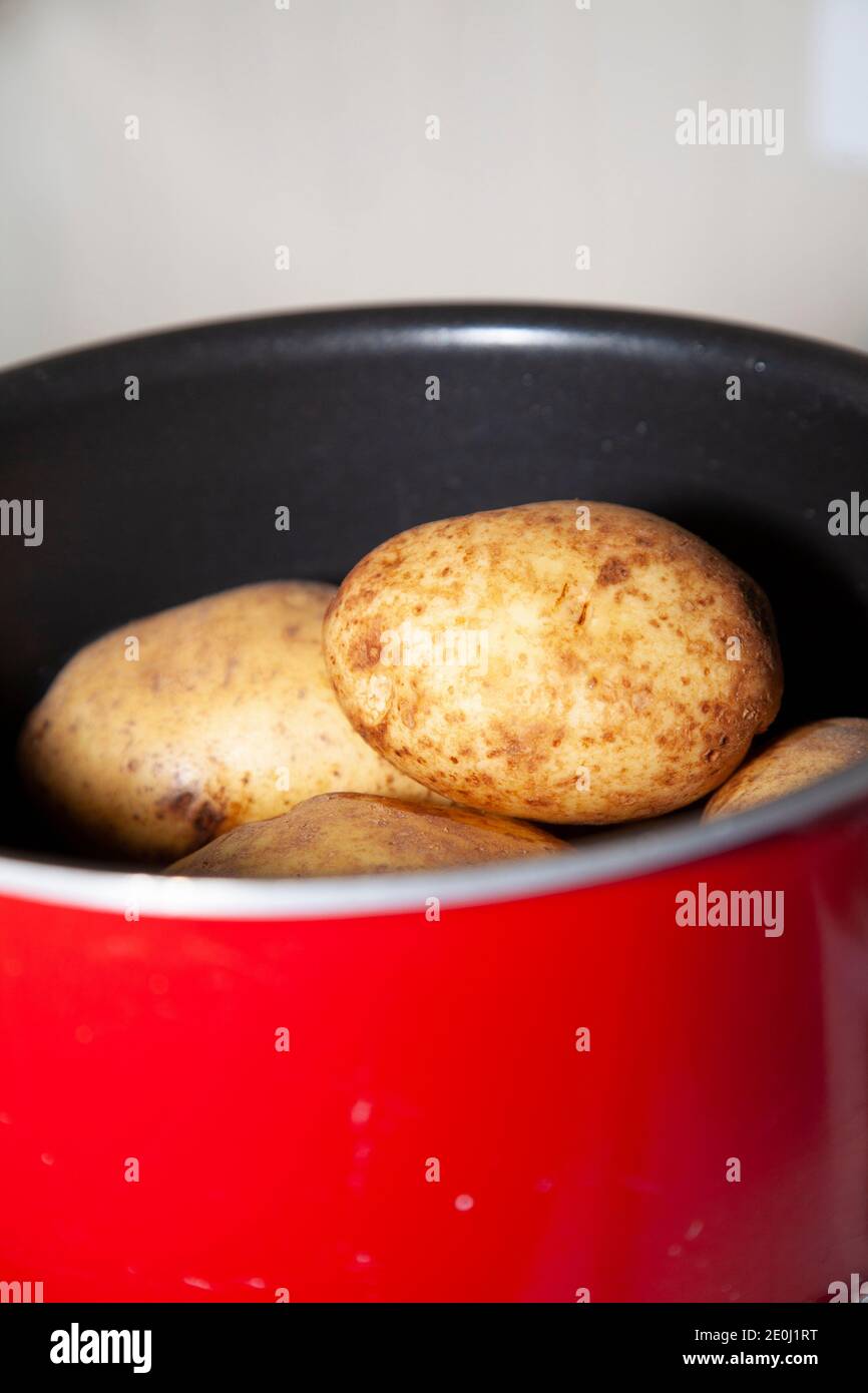Whole potatoes in a red and black boiling pan Stock Photo - Alamy