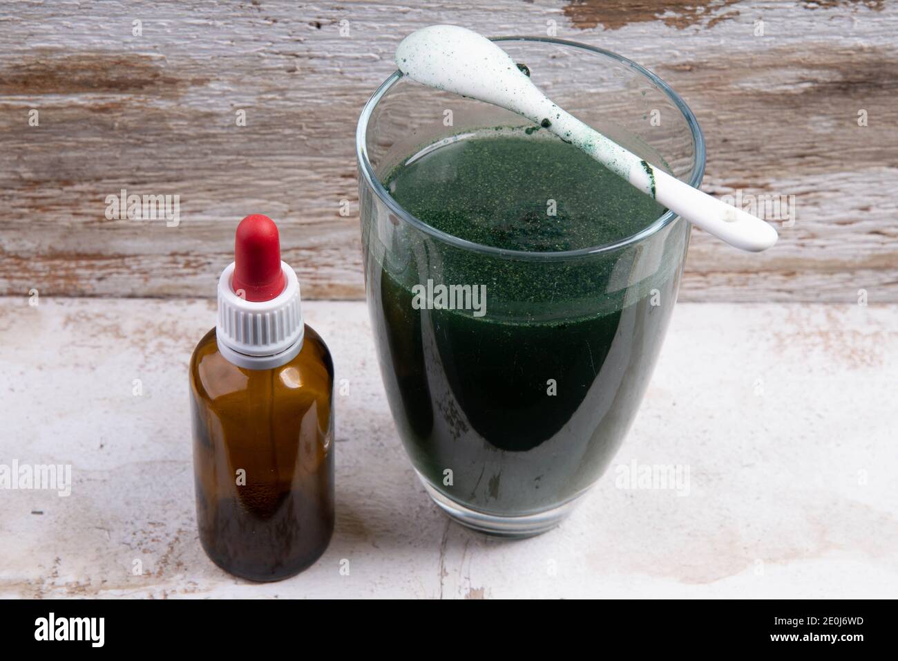 green dietary supplement stirred into a glass of water with dropper ...