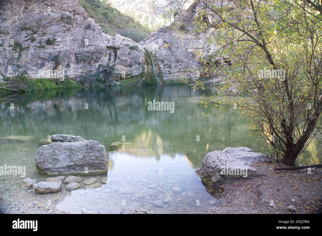 A waterfall cascades into a large pool with clear water in spain Stock ...