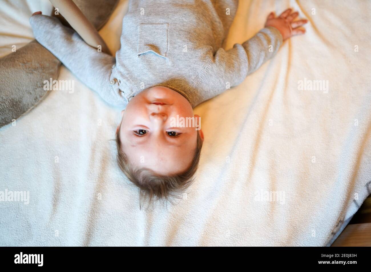 Adorable baby boy in white sunny bedroom. Newborn child relaxing in bed ...