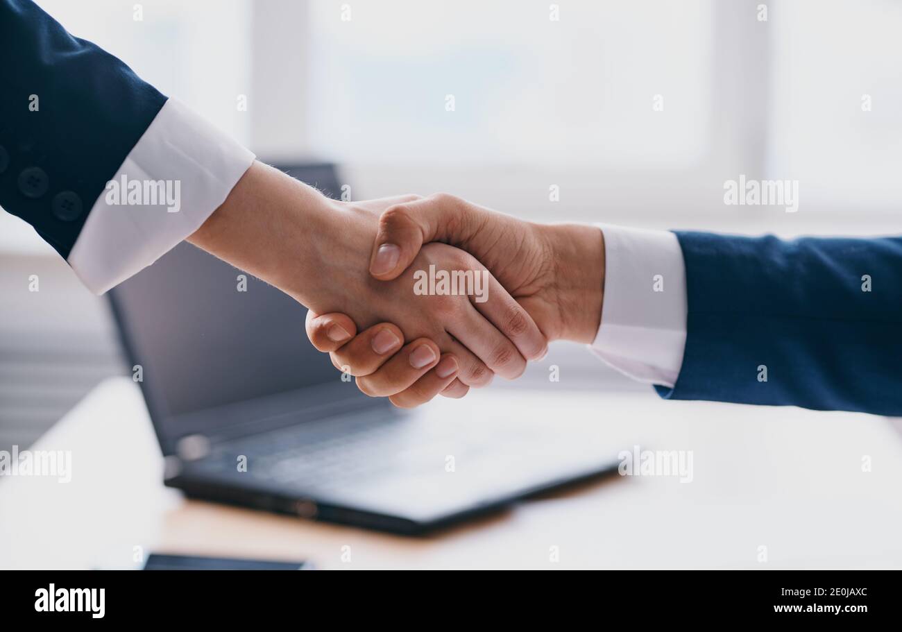 Business people shake hands on a light background office window laptop ...
