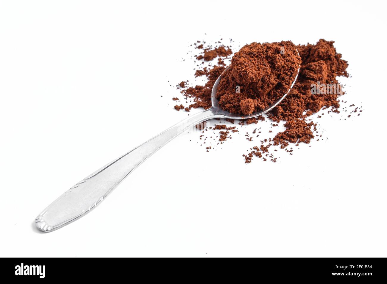 Silver teaspoon full of coffee in powder spilling on white background ...