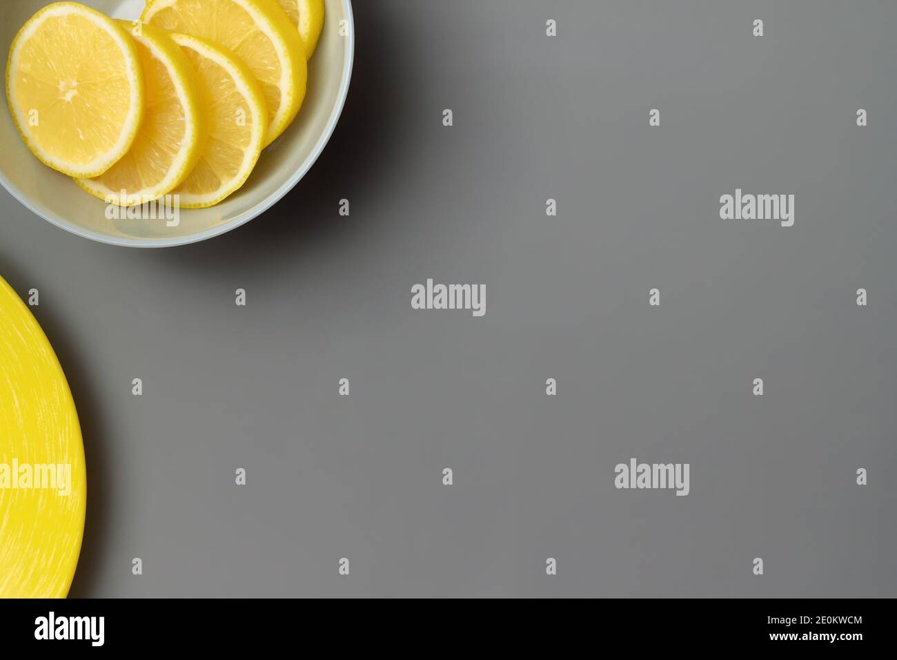 Yellow lemons in gray plate on gray background. Colors of the Year 2021 ...