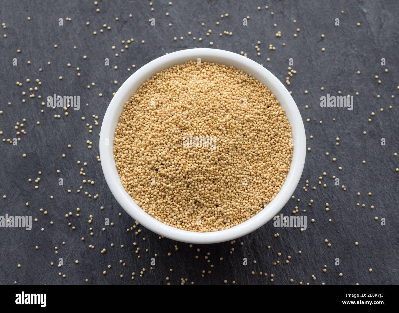 Raw amaranth seeds in a ceramic bowl on a dark shale background, top ...